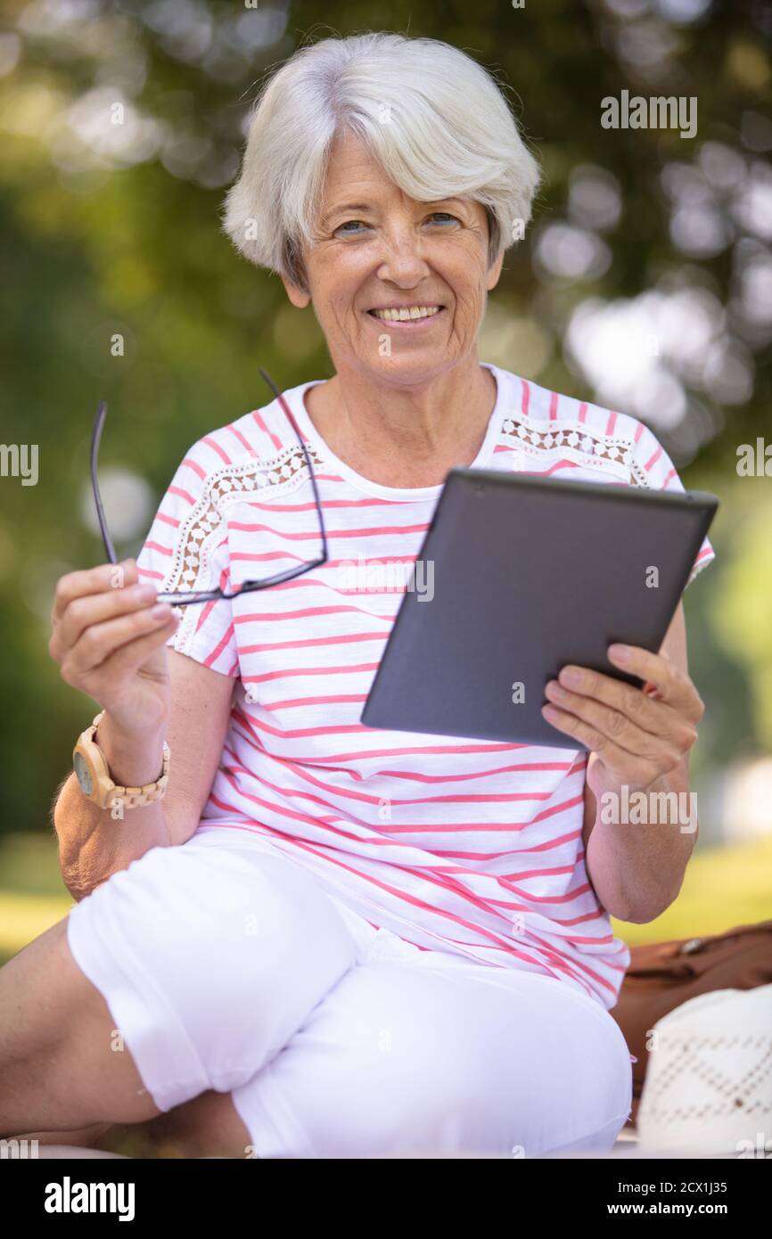 beautiful senior woman using tablet computer outdoors Stock Photo - Alamy