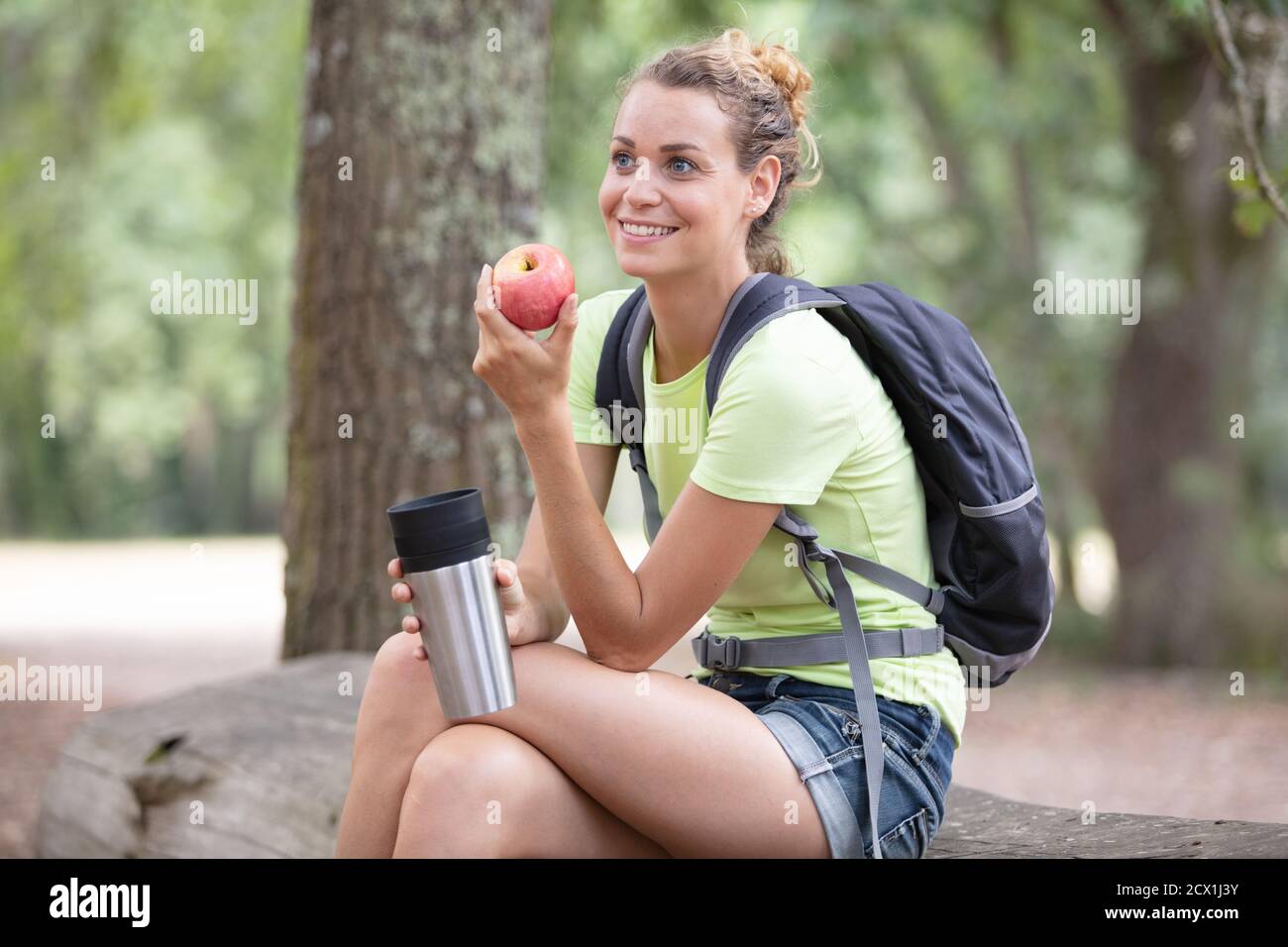 woman hiker resting and eating an apple sitting Stock Photo - Alamy