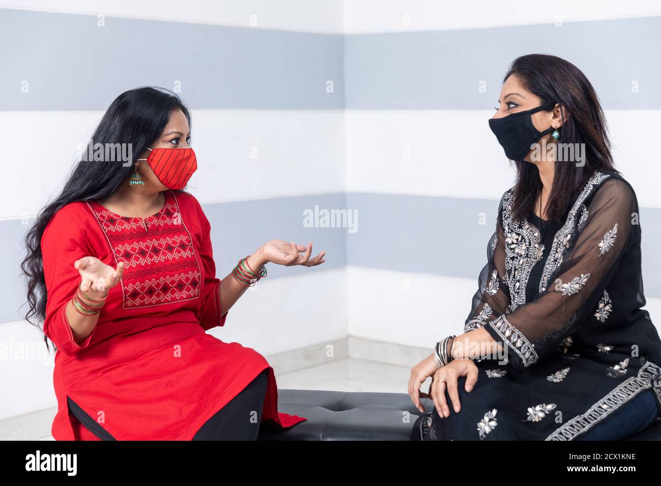 Portrait of two Indian women wearing Covid 19 protection mask, sitting ...