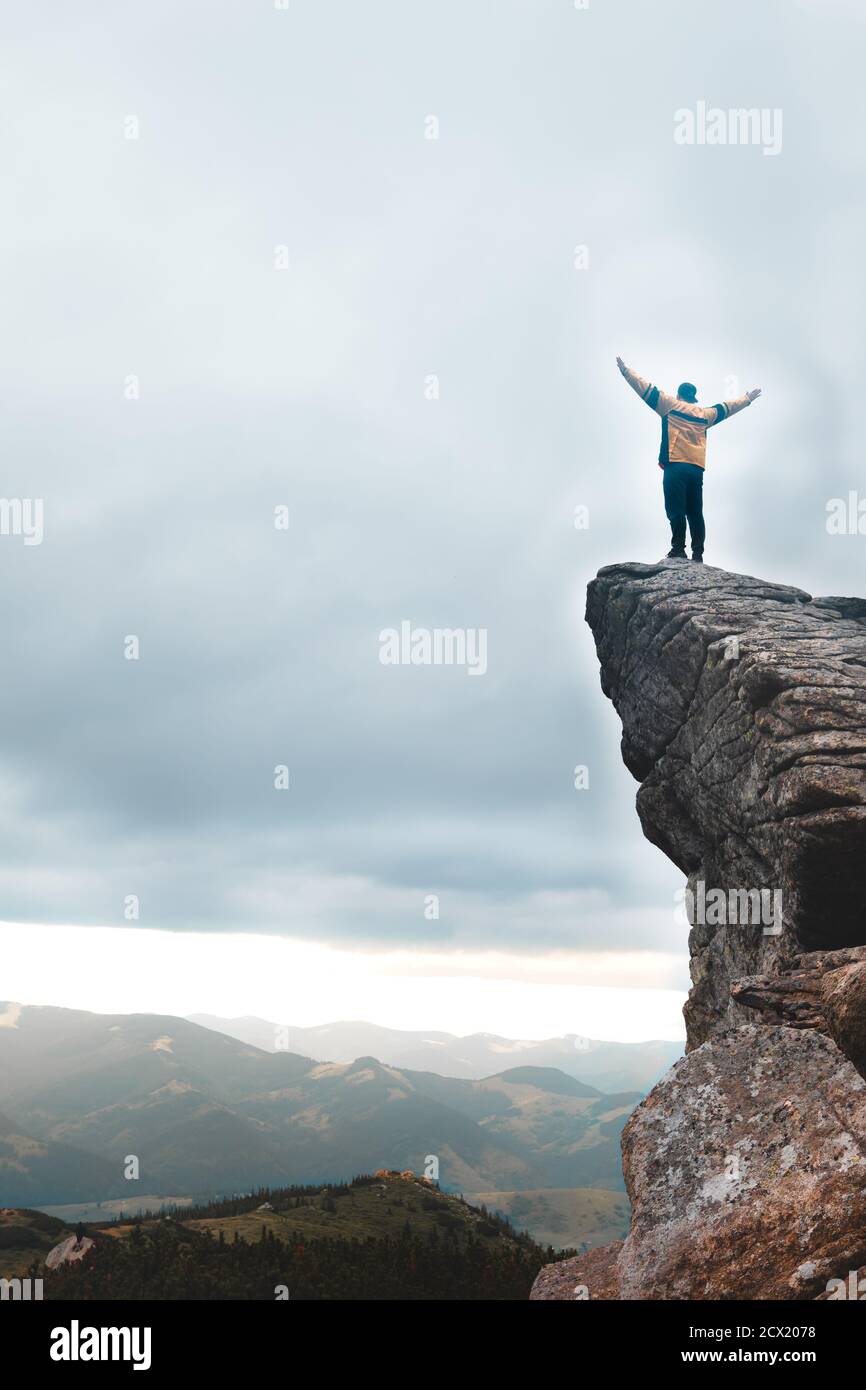 silhouette of the strong man at the edge of the cliff in mountains ...