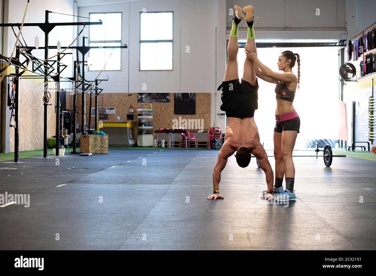 Young trainer helping a muscular man to do a handstand Stock Photo - Alamy