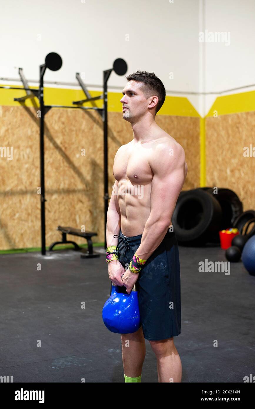 Strong man with dumbbell in hands doing strength exercises in the gym ...