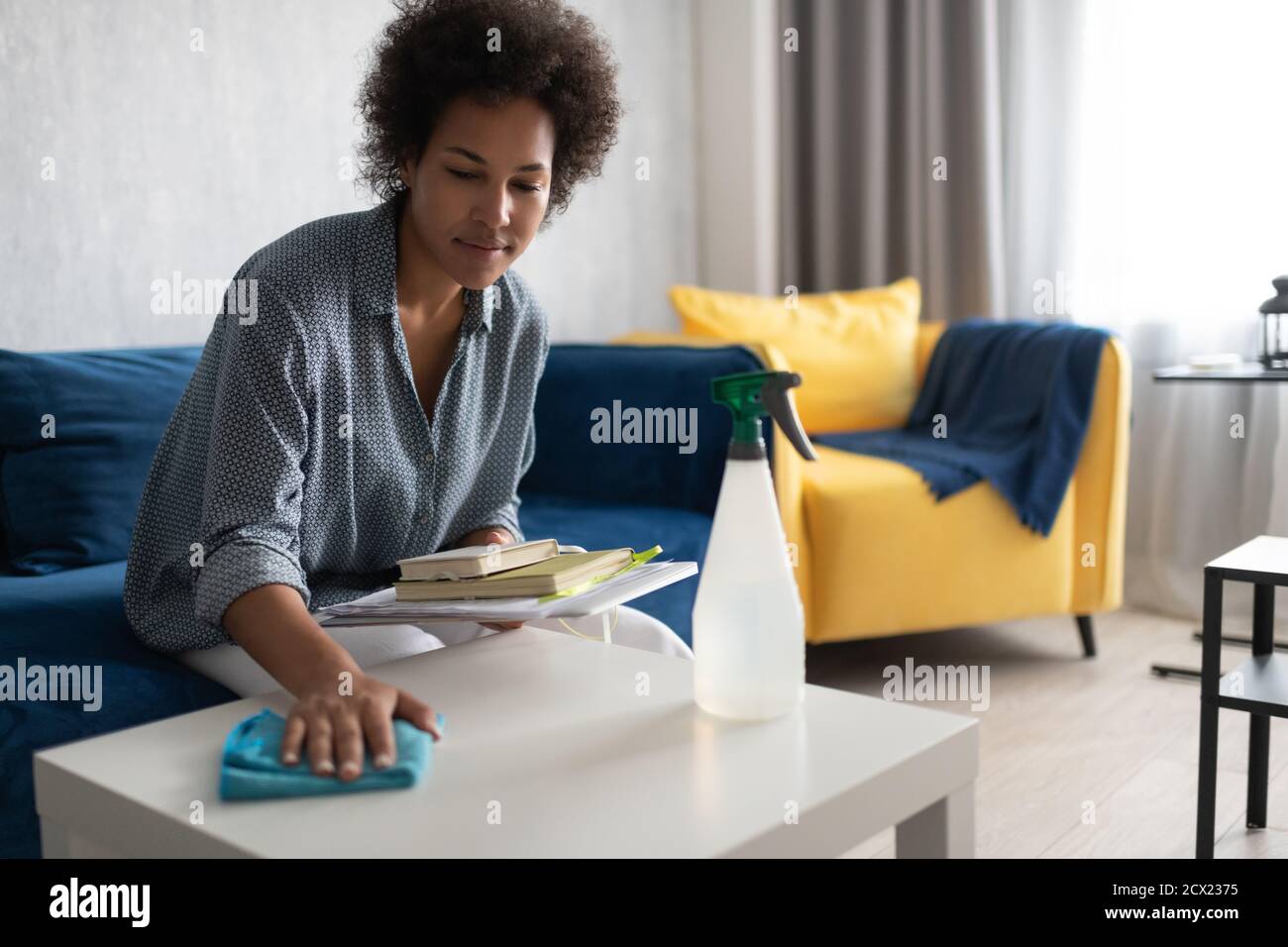 Adult African American female washing table with wet cloth while ...