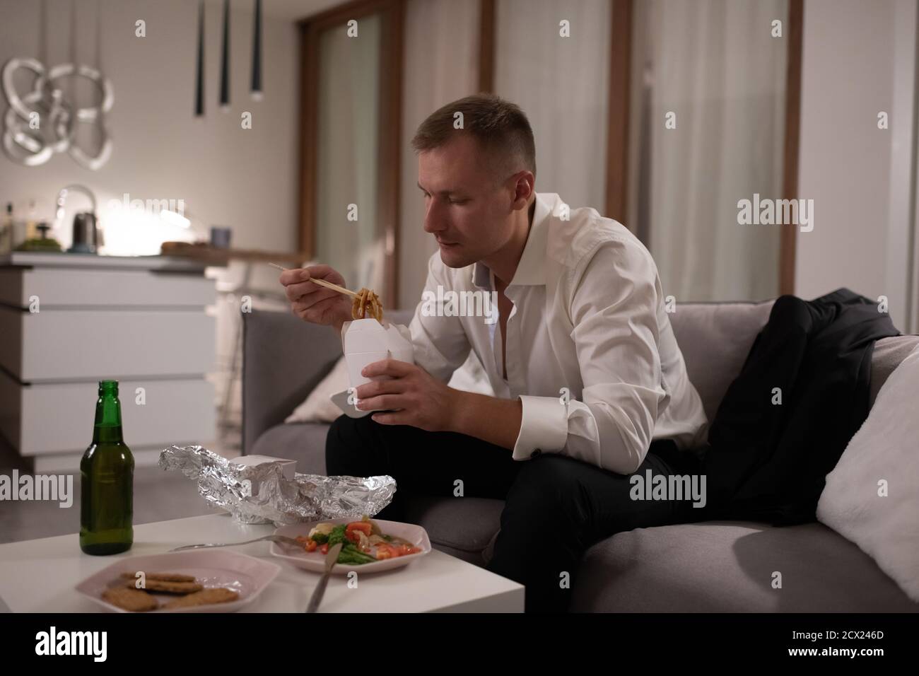 Adult male manager eating delivery noodles while resting after work at ...