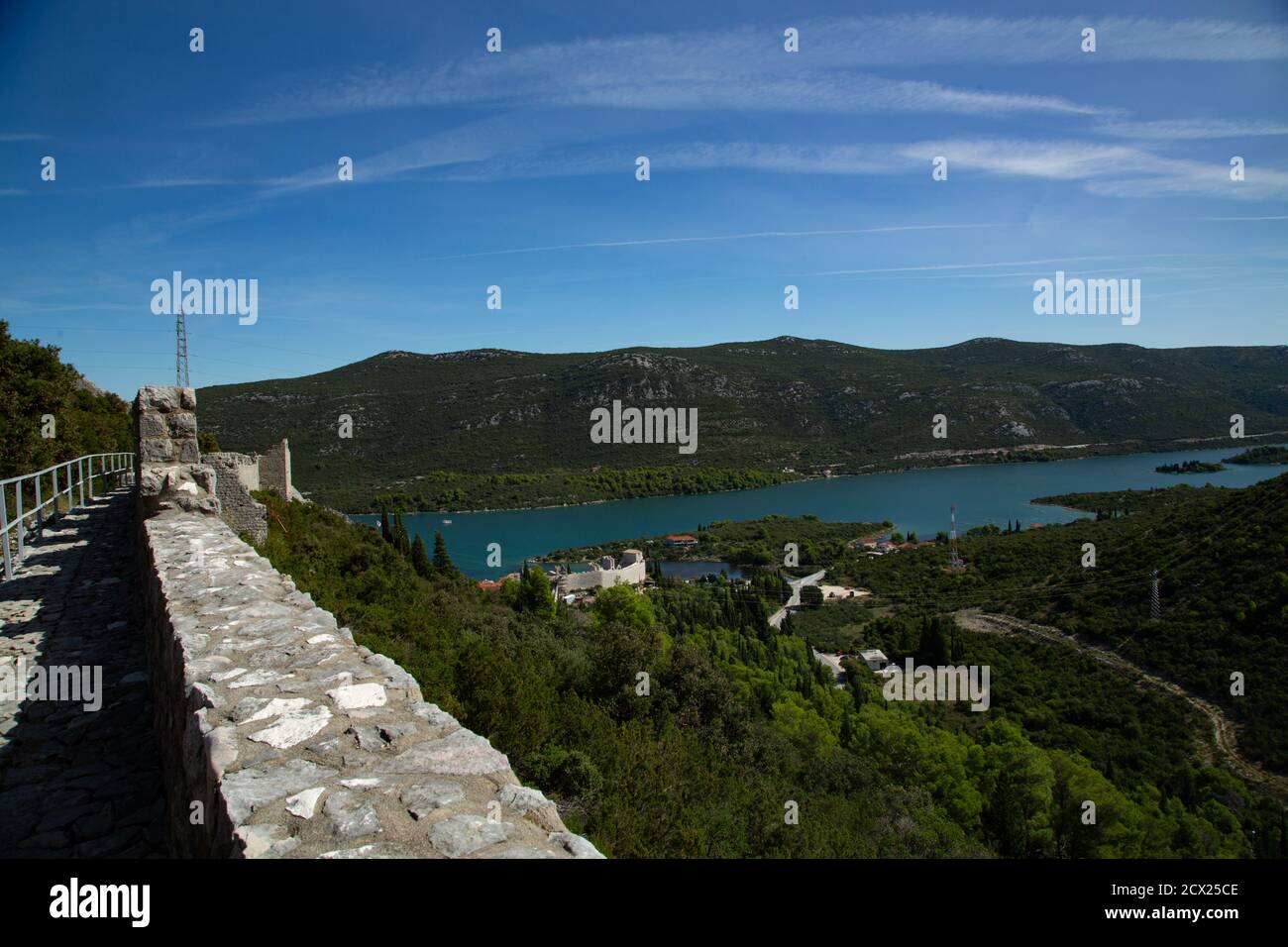 Wall on mountainside above valley and sea inlet in the background Stock ...