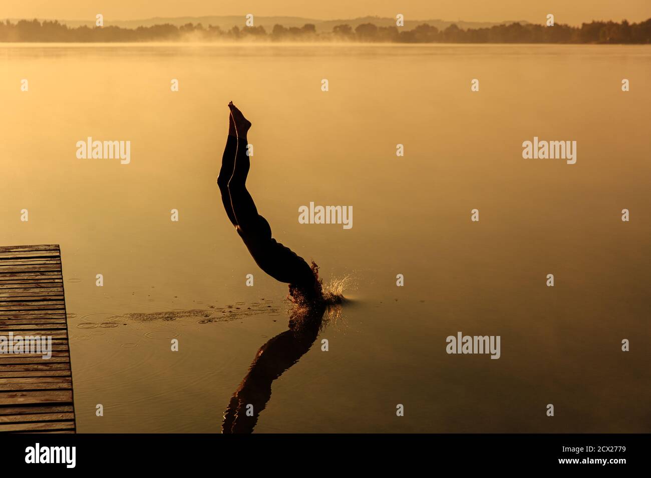 Muscular swimmer plunge into water from wooden pier Stock Photo - Alamy