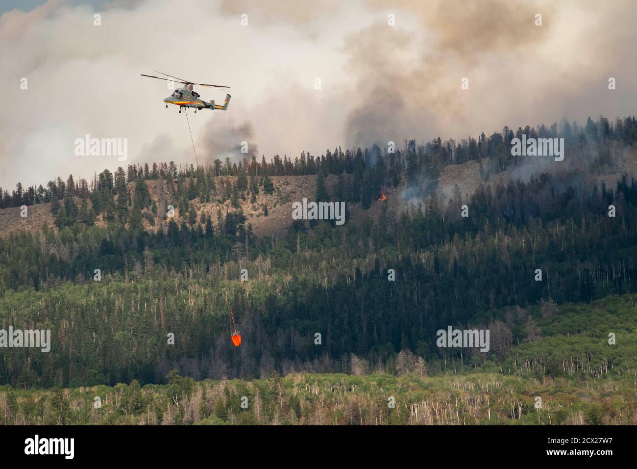 Military helicopter flying with fire retardant while smoke emitting ...