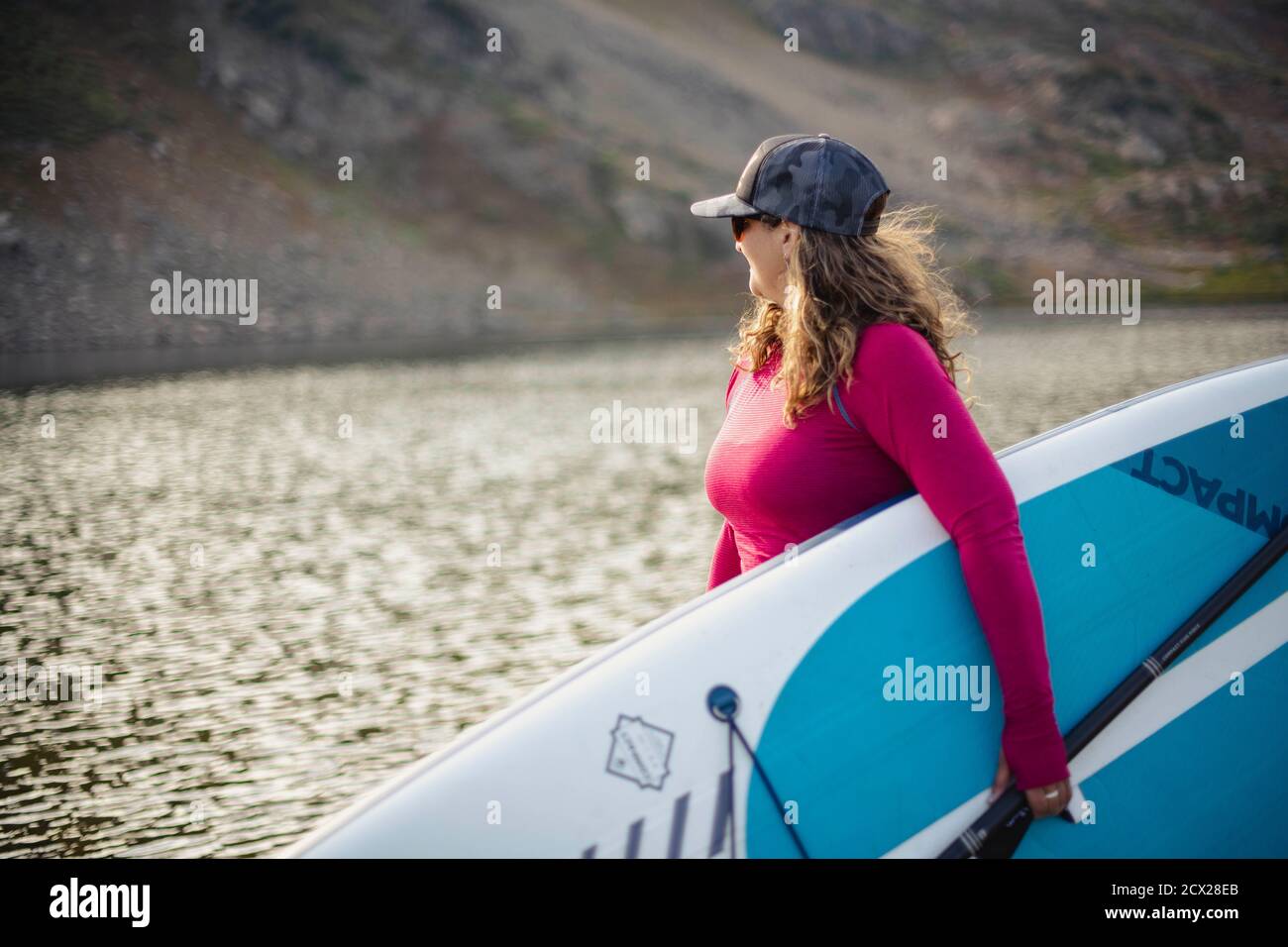 Side view of woman carrying paddleboard by lake Stock Photo - Alamy