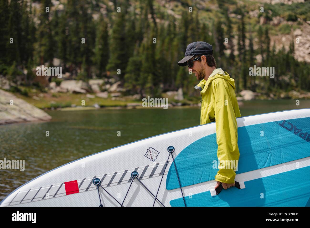 Side view of man carrying paddleboard Stock Photo - Alamy
