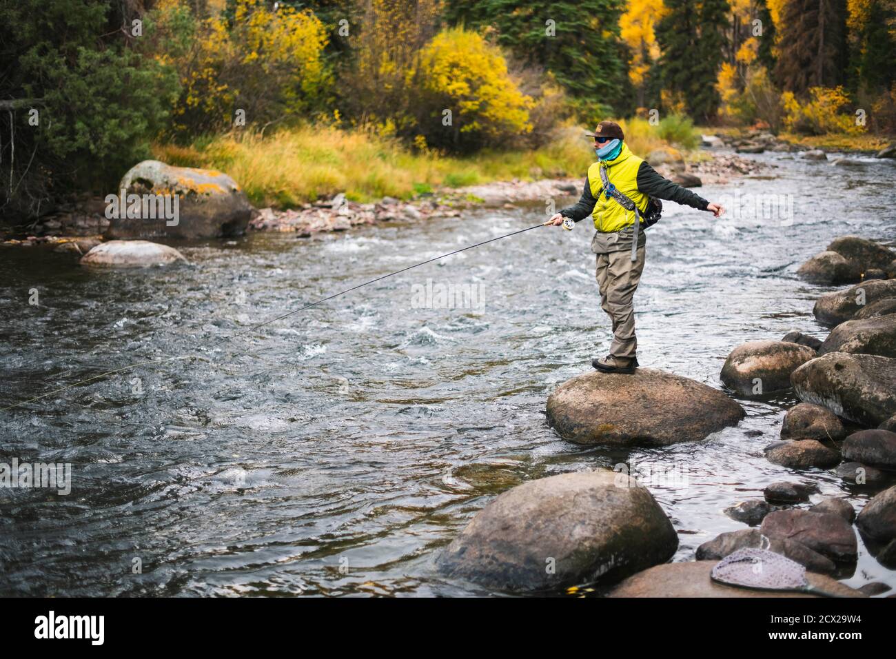 Man fly fishing while standing on rock at Roaring Fork River during ...
