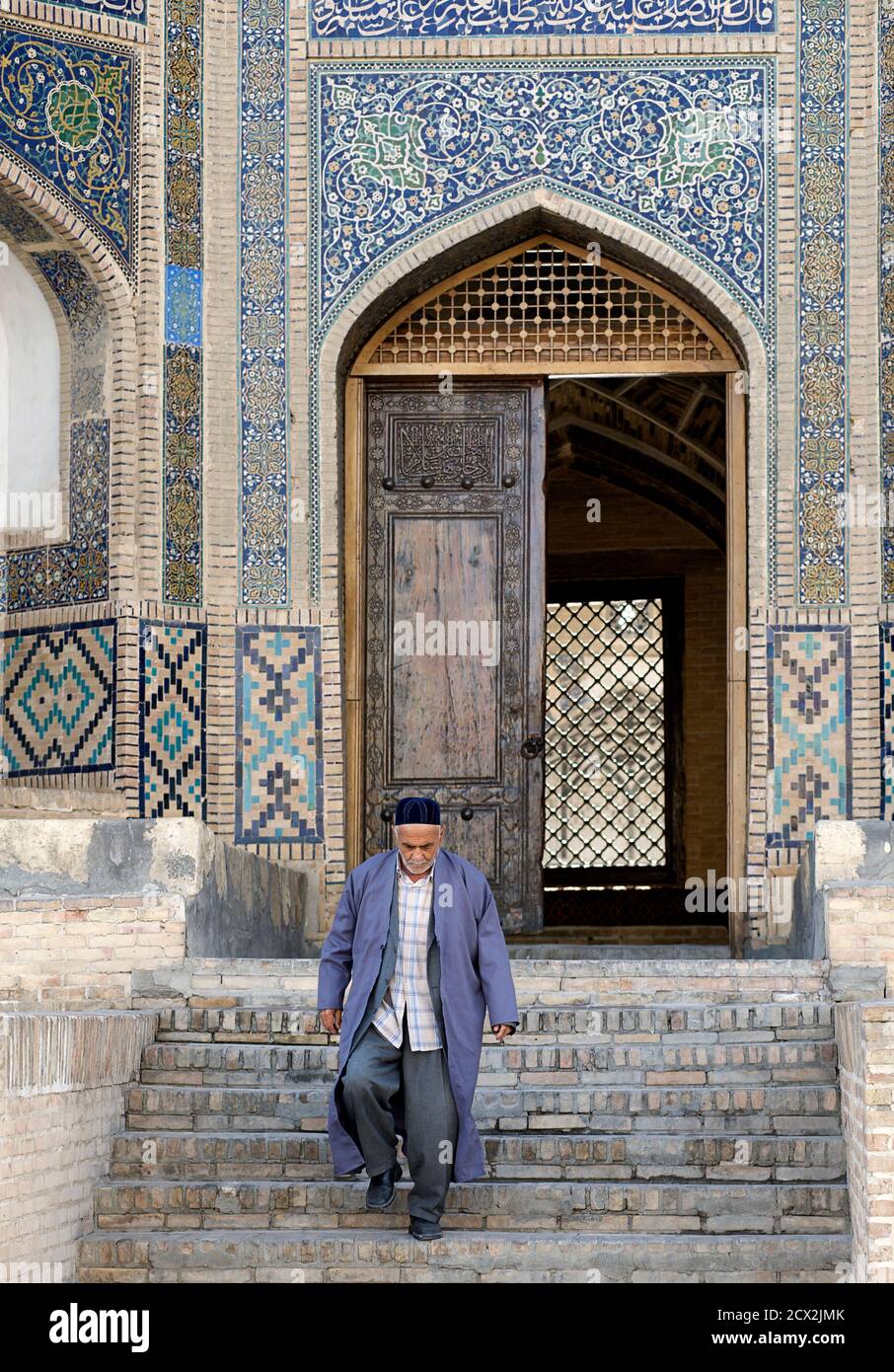 Uzbeki man walking down steps from the Mir-i-arab Madrassah, Bukhara ...