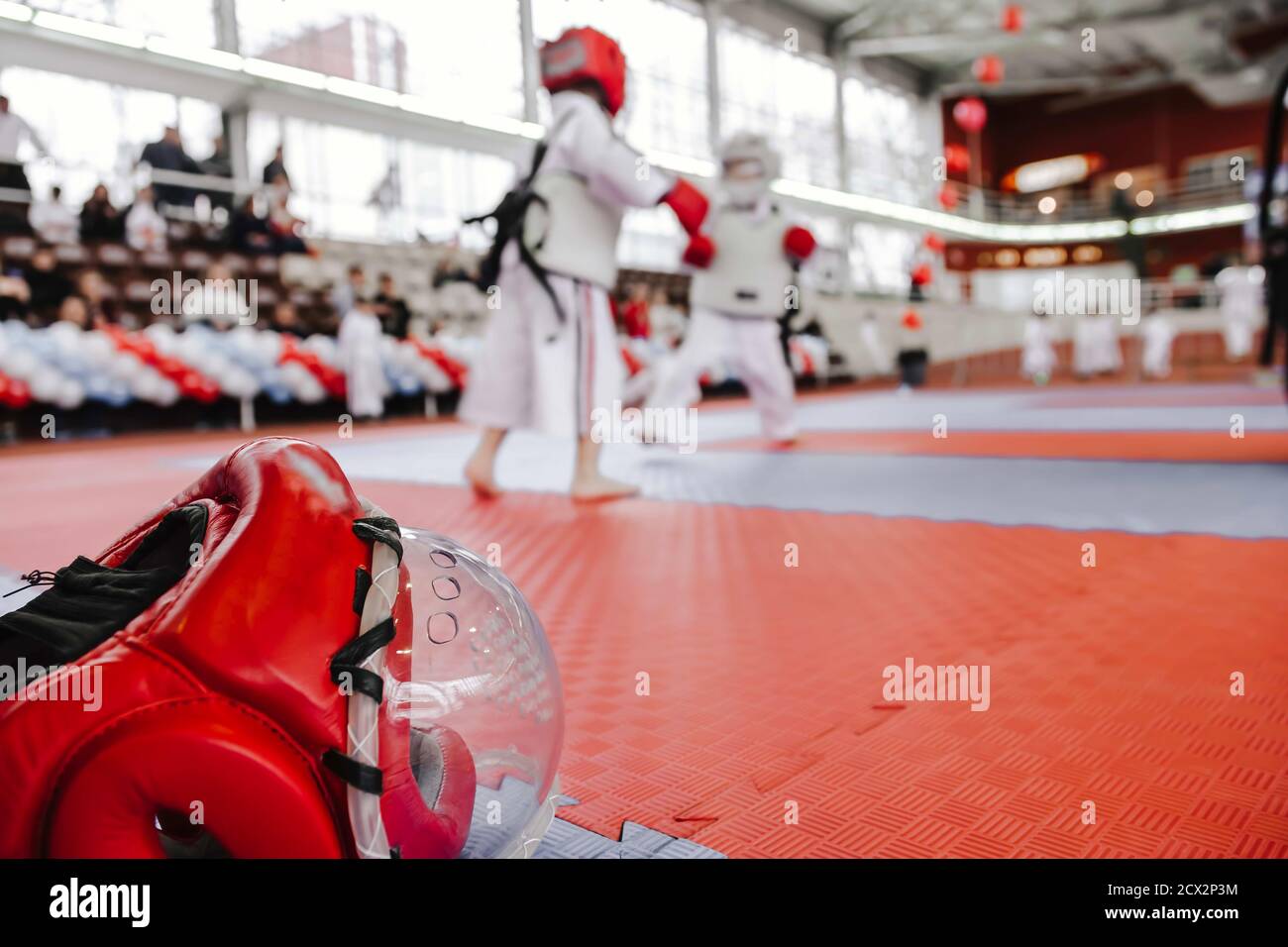Red fighting helmet with clear plastic mask on the floor at foreground ...