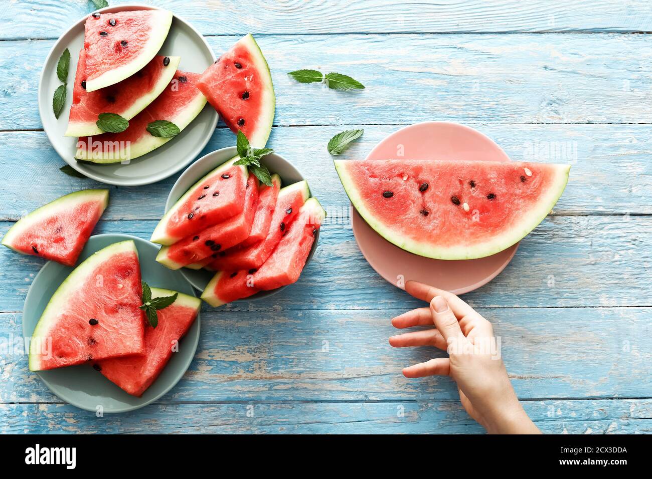 Fresh red watermelon slice, female hand on an blue rustic wood ...