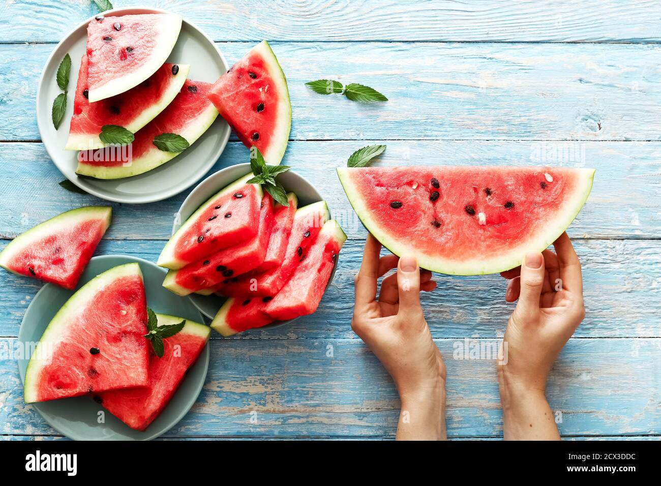 Fresh red watermelon slice in female hands on an blue rustic wood ...