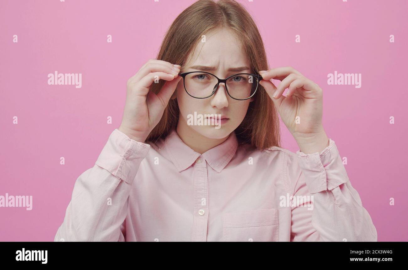 Distrustful frowning lady touching glasses Stock Photo - Alamy