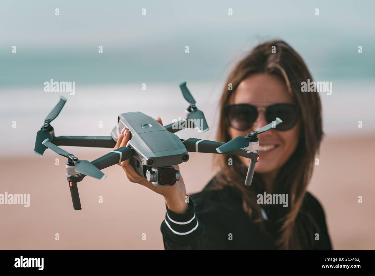 Cute modern lady pilot holds drone in her hand. Outdoors hobby. Focus ...