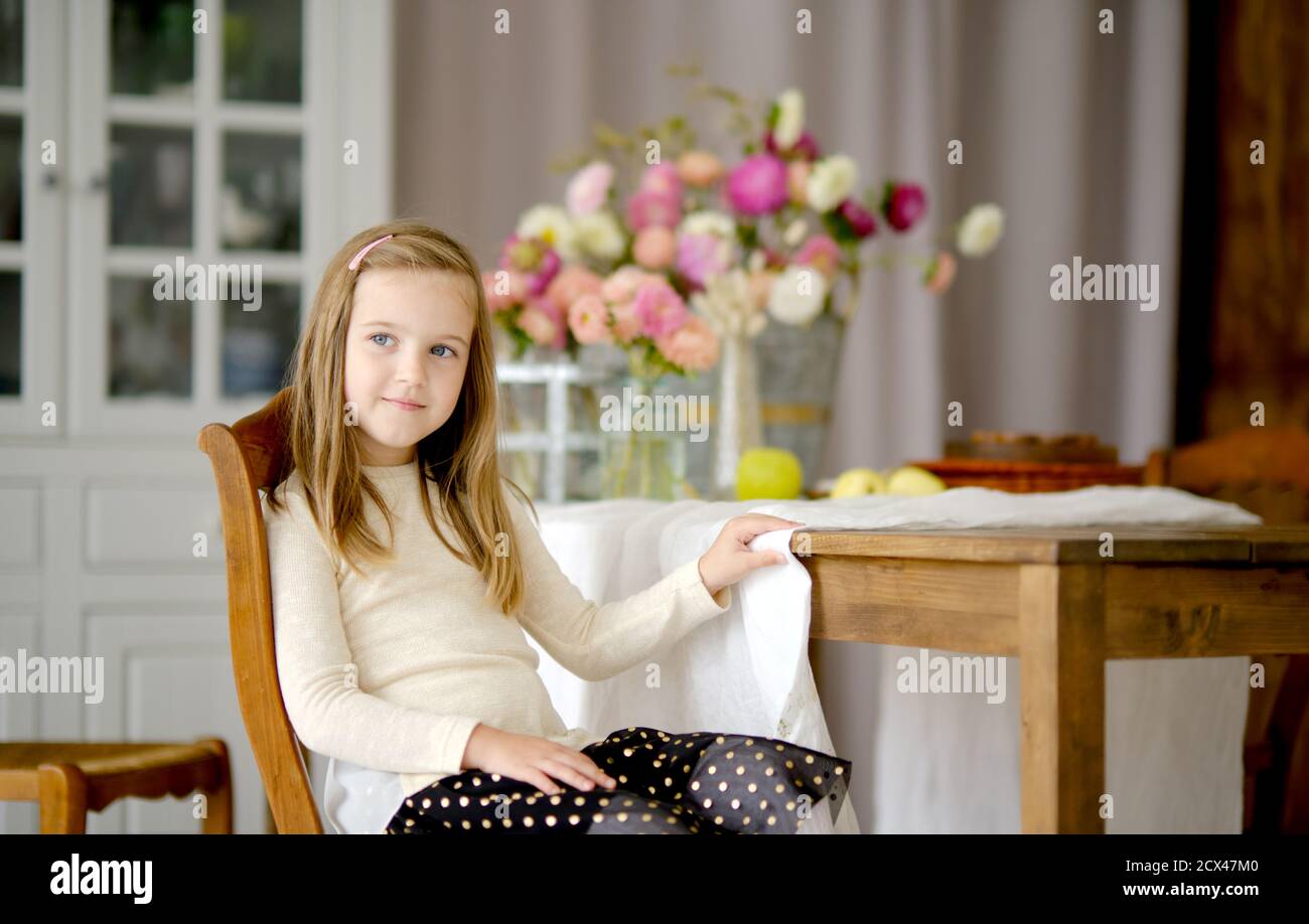 Young cute girl sitting behind the kitchen table Stock Photo - Alamy