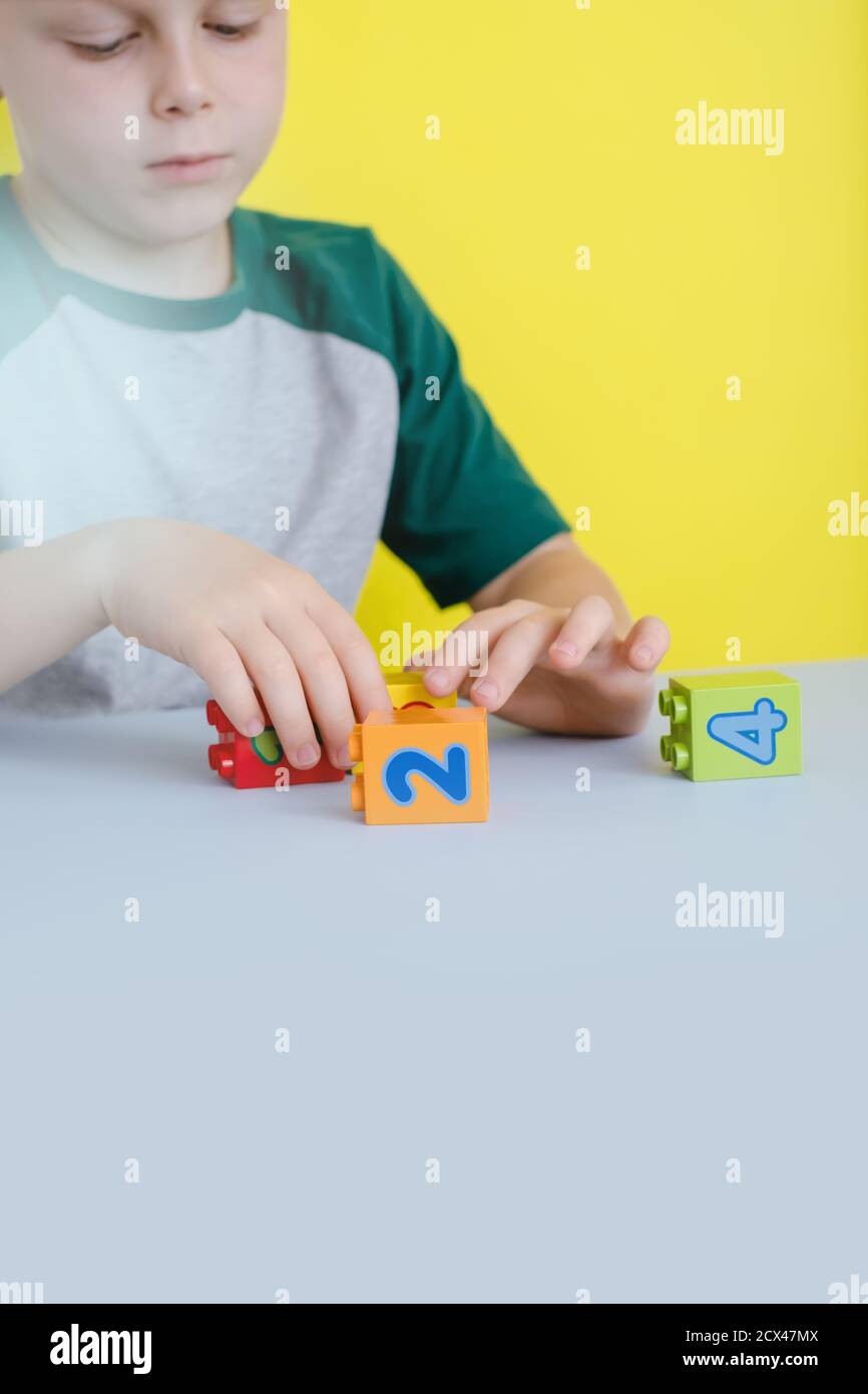 The child playing with cubes with numbers on the table.On a yellow ...
