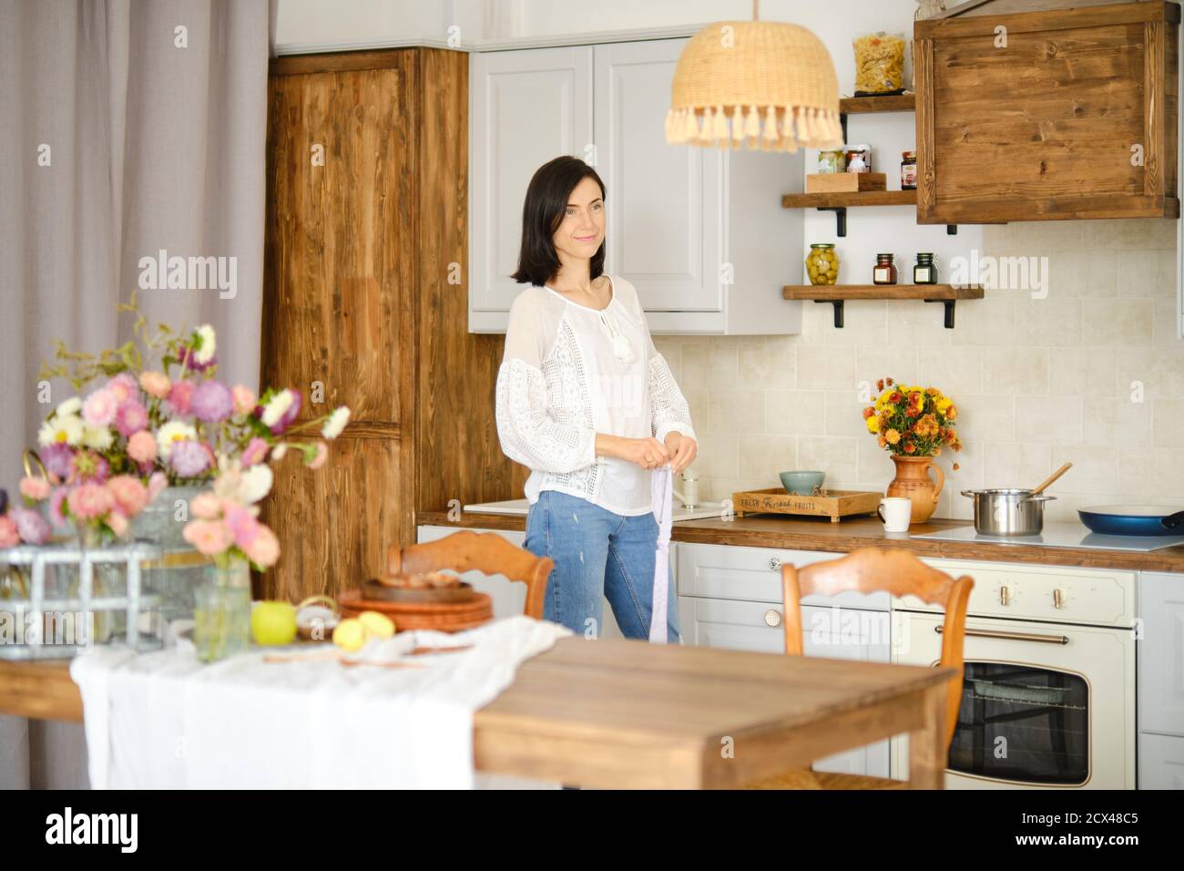 Portrait of pretty woman in casual clothes in the kitchen with cup of ...