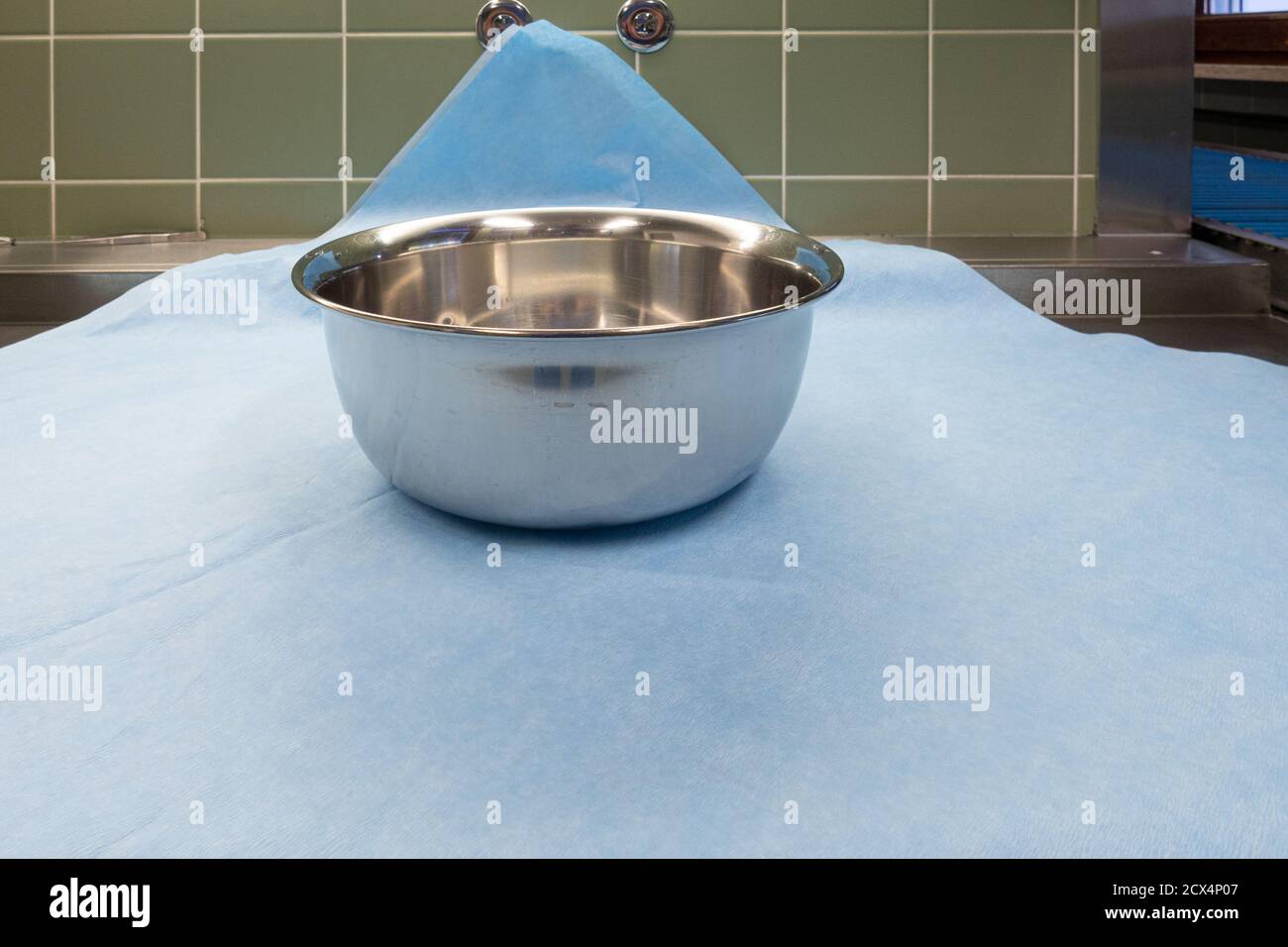 a large silver saline bowl is wrapped in a blue paper towel in an ...