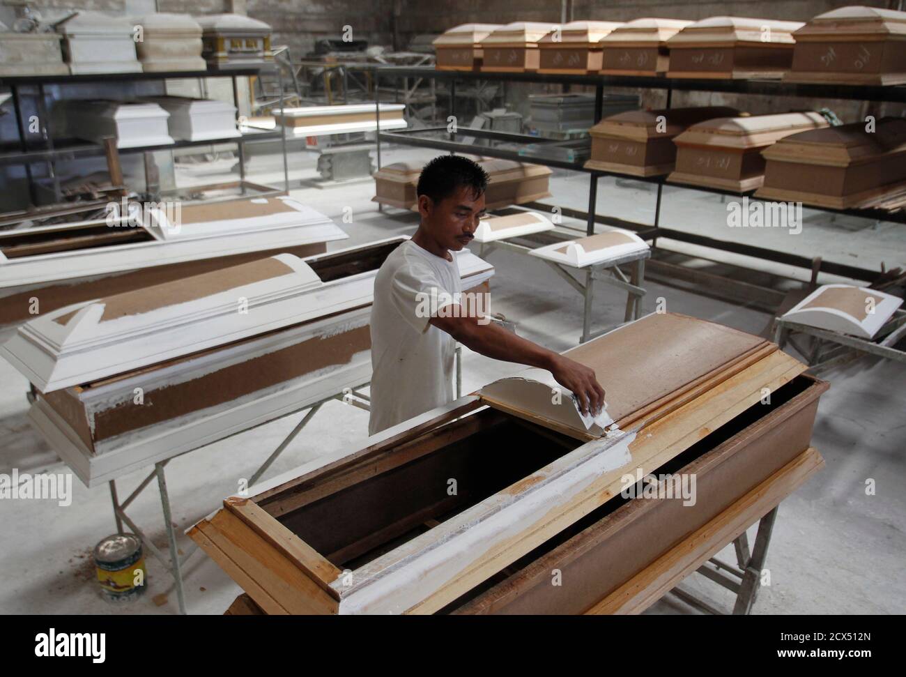A worker builds a coffin inside a warehouse of a casket manufacturing ...