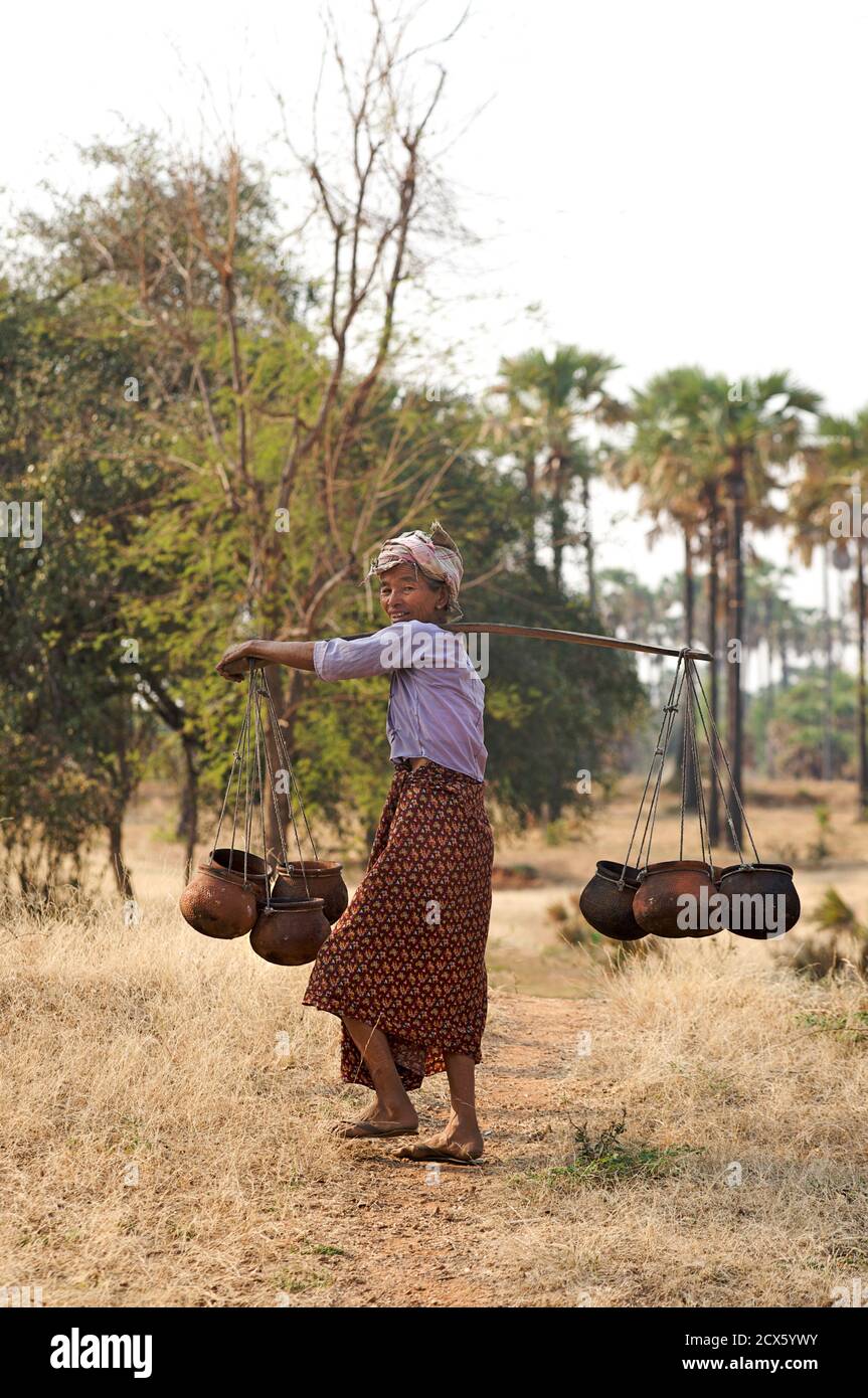 Burmese woman transporting water in ceramic pots. Near Mount Popa ...