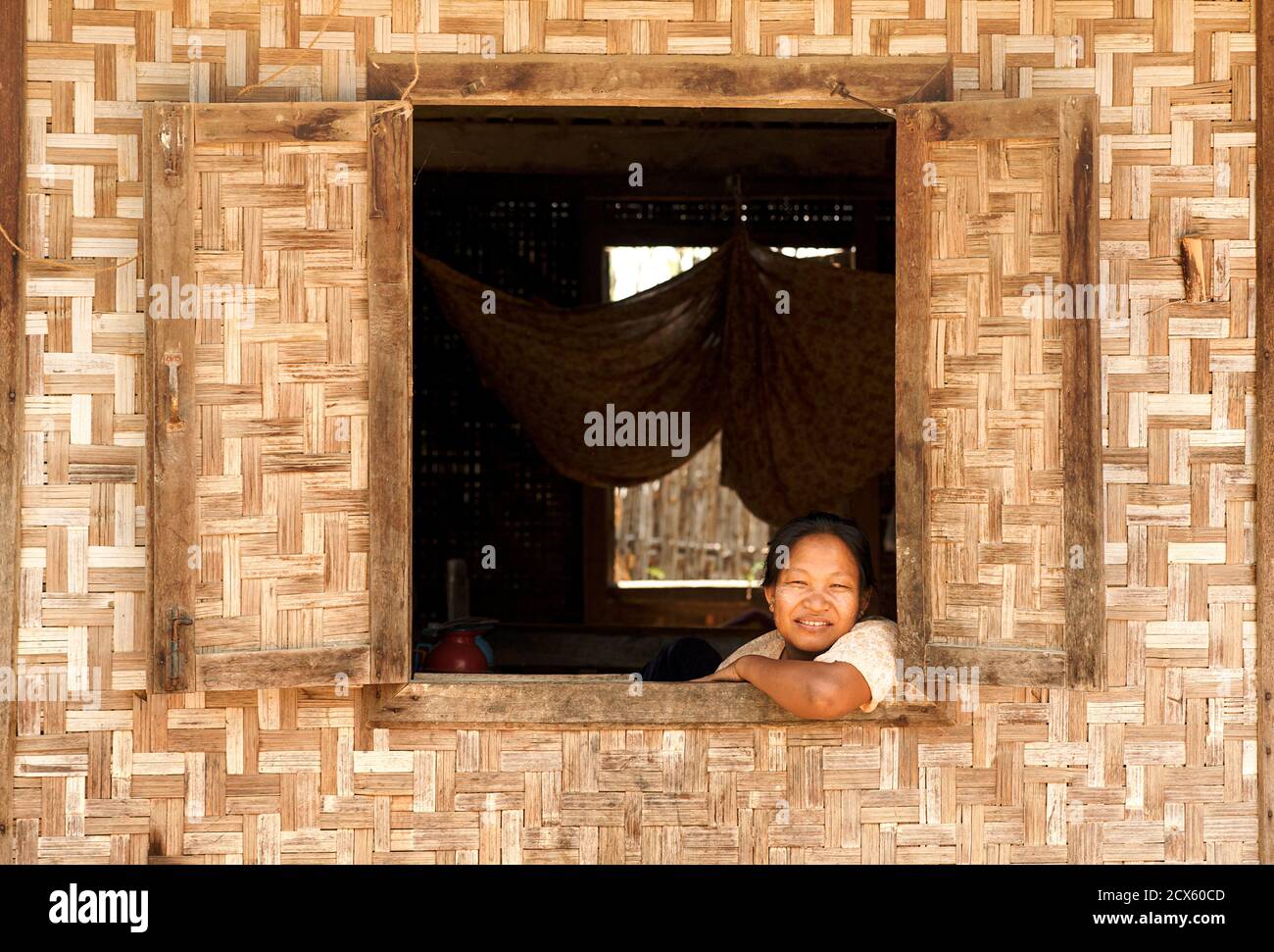 Burmese woman in the window of her home. Near Monywa, Sagaing Region ...