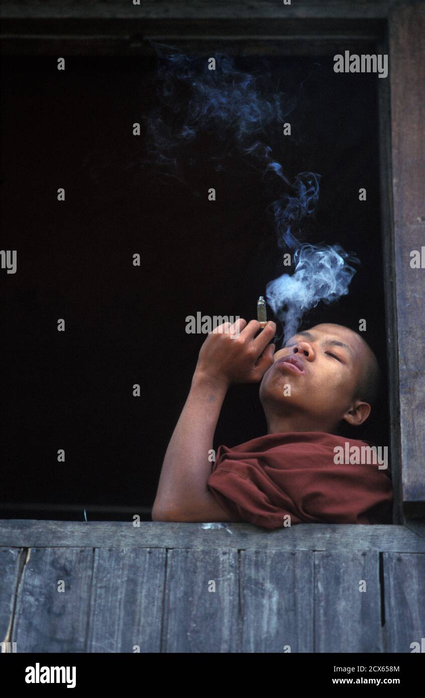 Monk smoking from the window of his quarters, Shwe Min Bone village ...