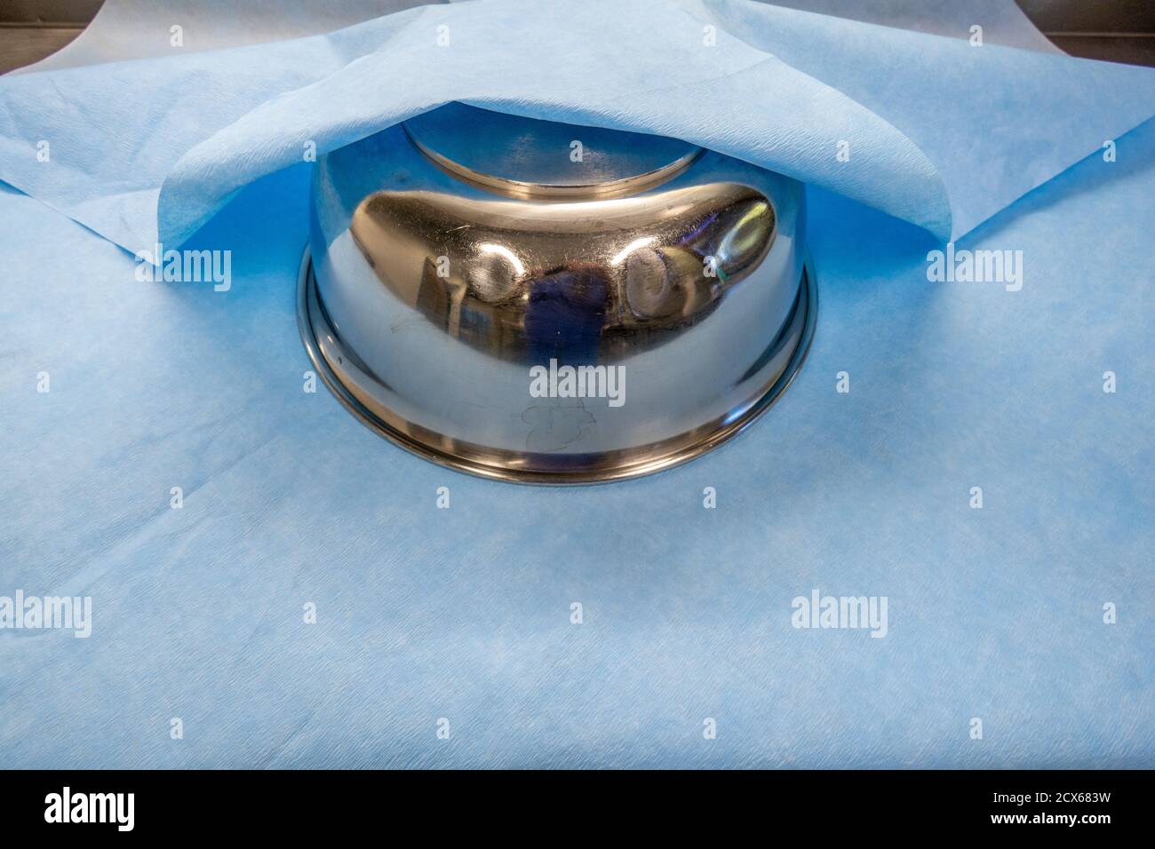 a large silver saline bowl is wrapped in a blue paper towel in an ...