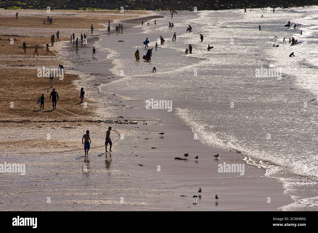 Silhouettes of summertime beachgoers in the surf at St Ives, Cornwall ...
