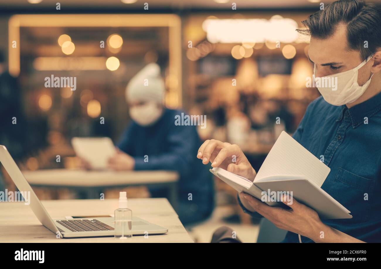 young man reading a book sitting at a table in the food court Stock ...