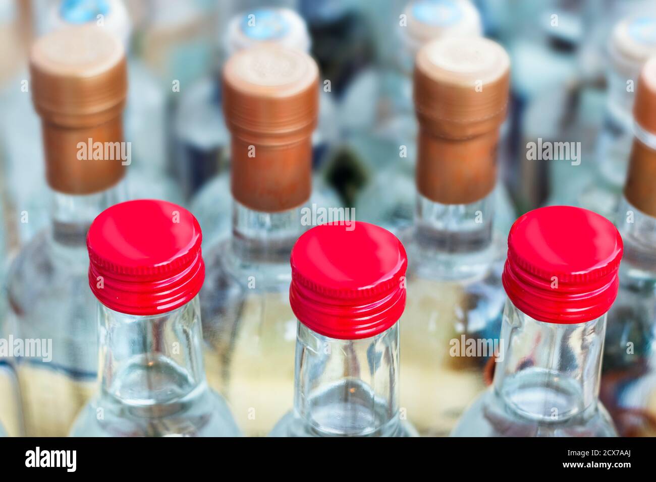 Close up of red screw taps on small transparent bottles placed in a row ...