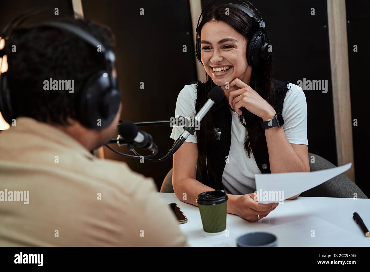 Portait of happy female radio host smiling, listening to male guest ...