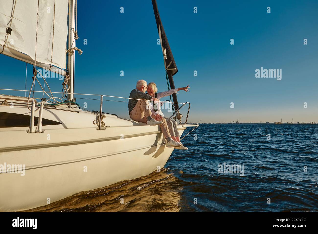 Sailing. Happy retired family couple sitting on the side of a sail boat ...