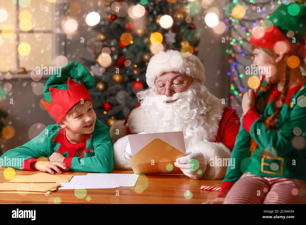 Elf kids with Santa Claus reading letter at home Stock Photo - Alamy