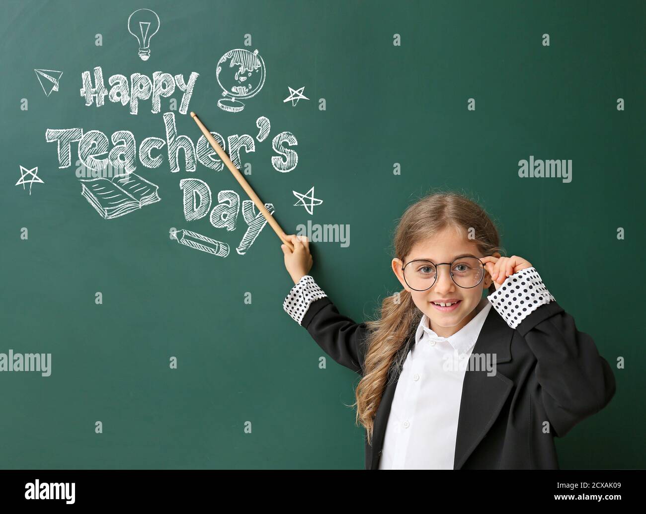 Cute little schoolgirl with pointer near blackboard with text HAPPY ...