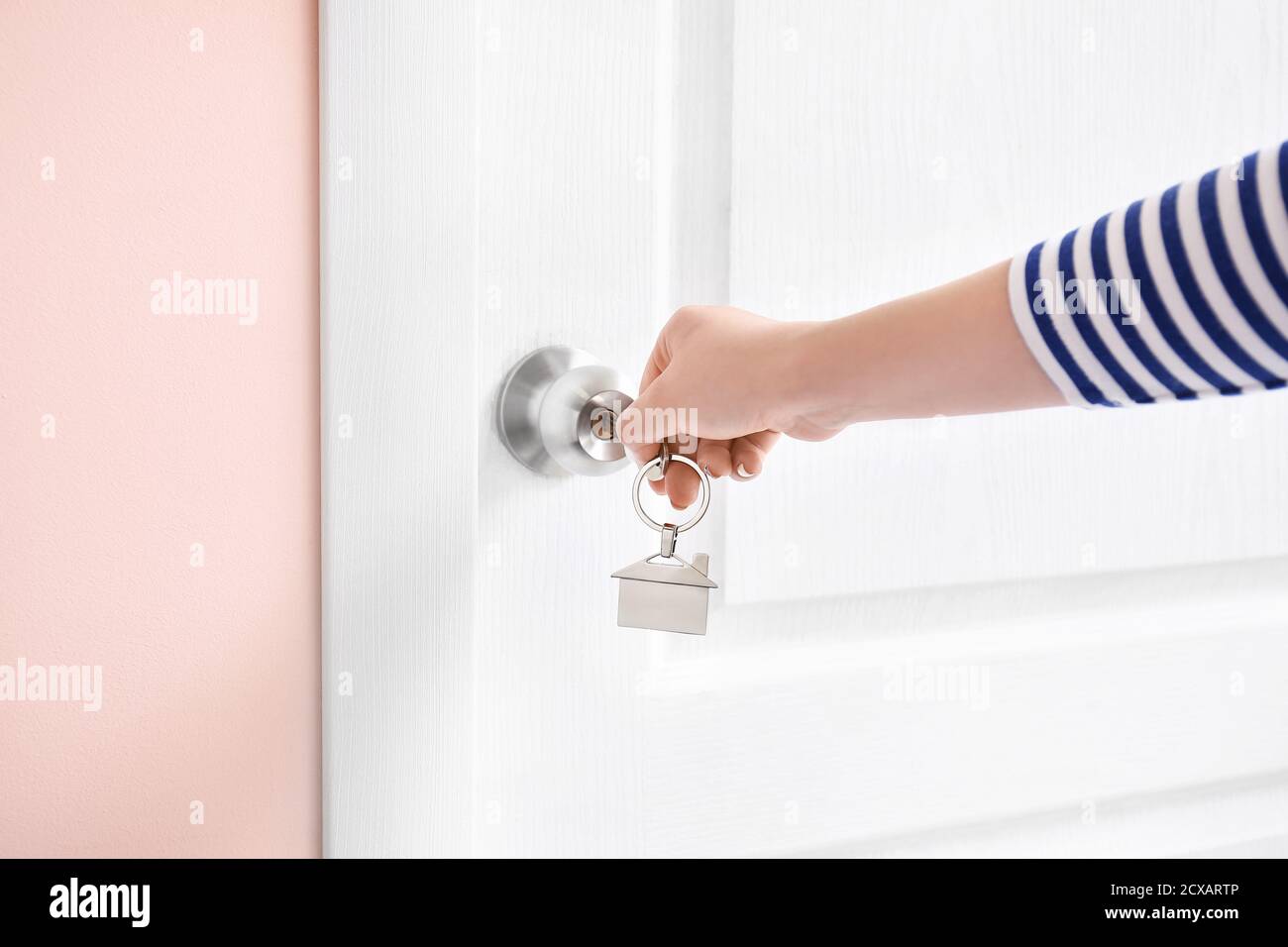 Woman using key to open door indoors Stock Photo - Alamy