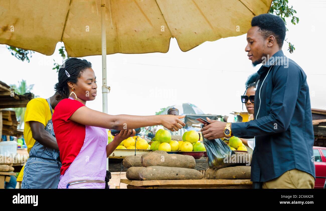 group of young africans making transaction happening in a market place ...