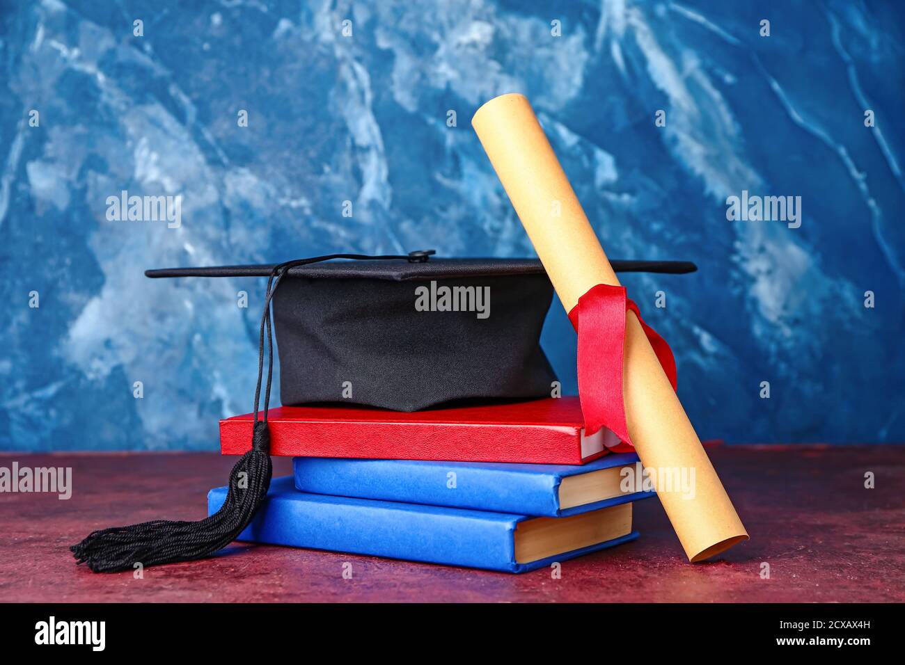 Graduation hat, diploma and books on color background Stock Photo - Alamy