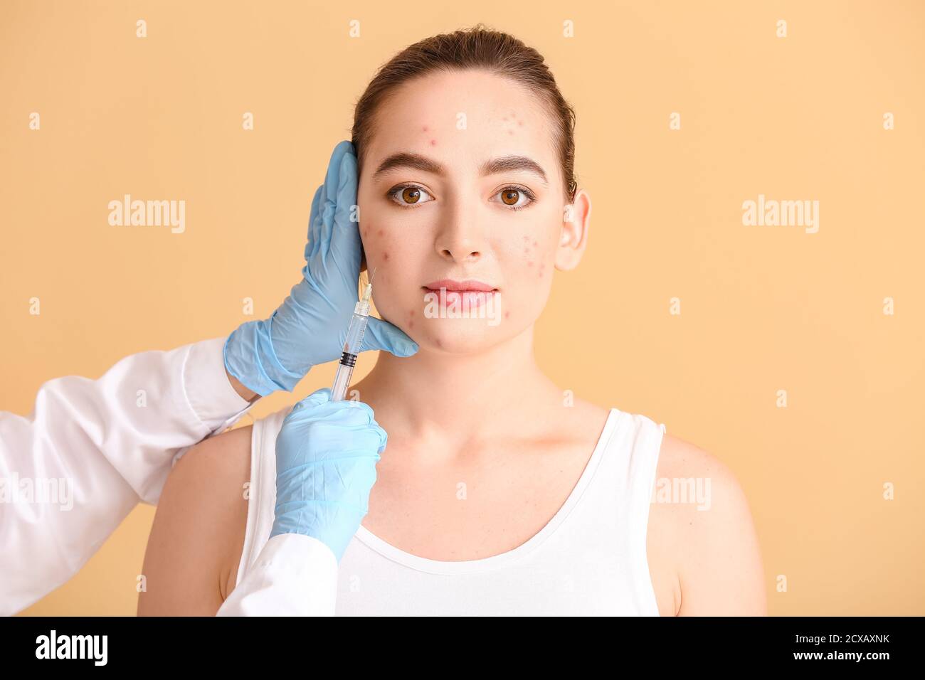 Young woman with acne problem receiving injection in her face against ...