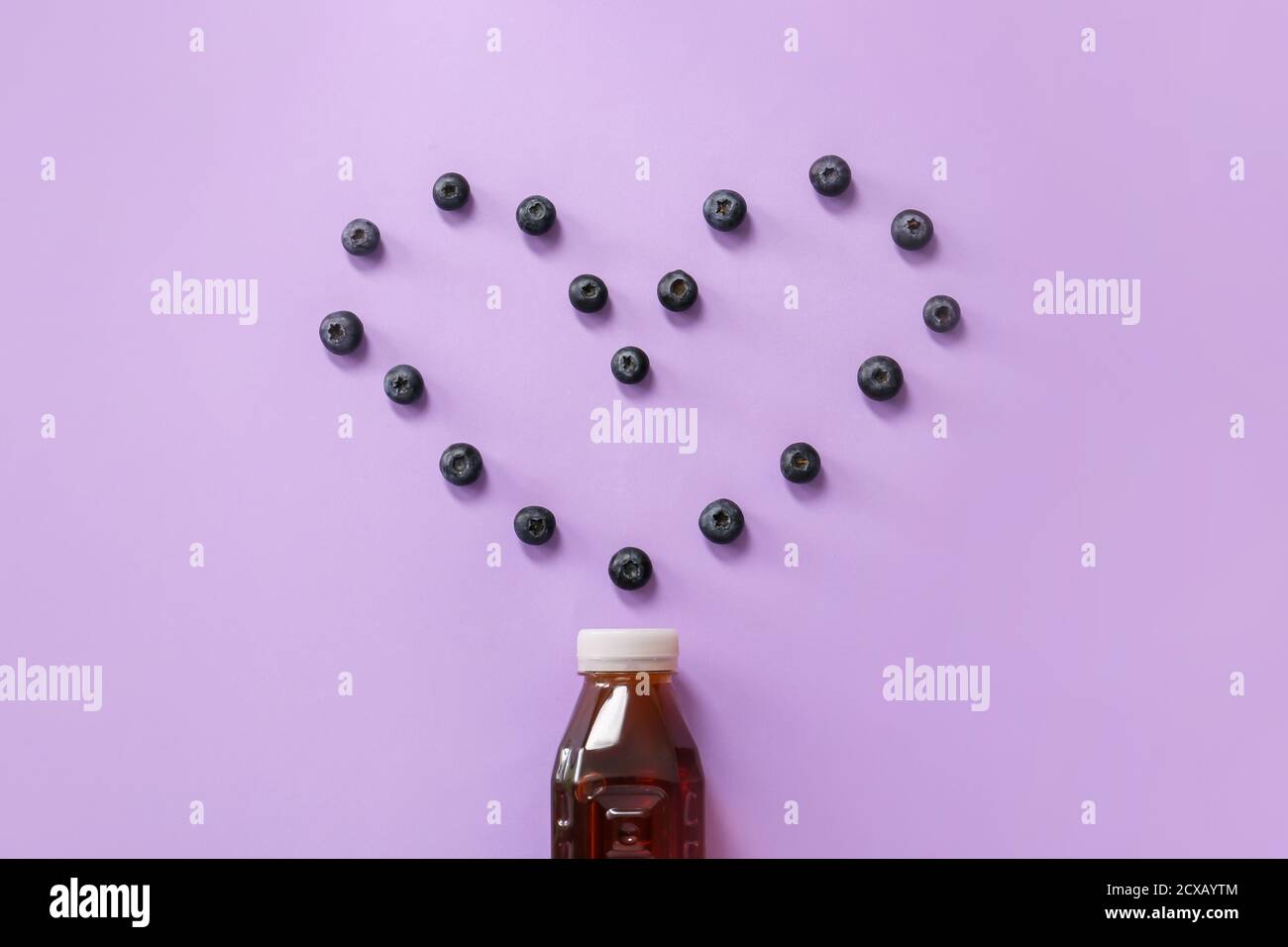 Bottle of fresh ice tea and heart made of berries on color background ...