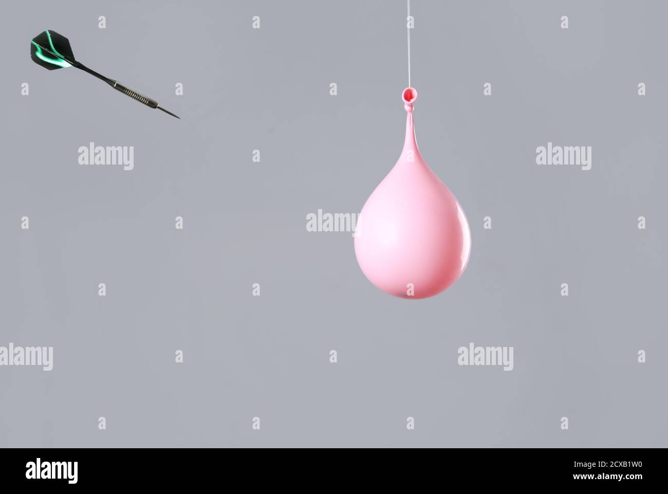 Throwing of dart in balloon with water on grey background Stock Photo ...
