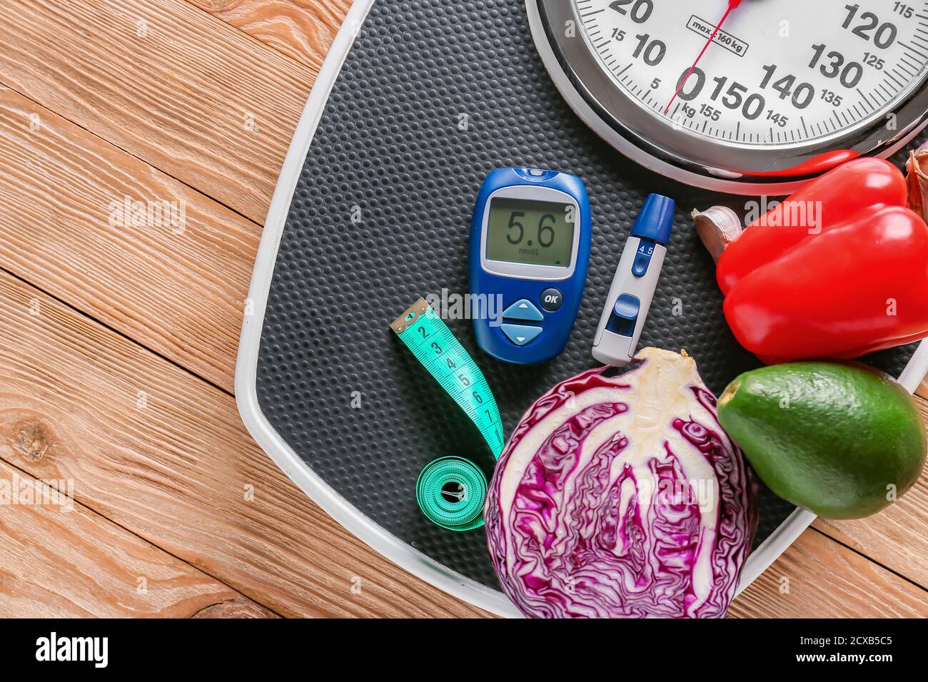 Vegetables, scales, measuring tape, lancet pen and glucometer on wooden ...