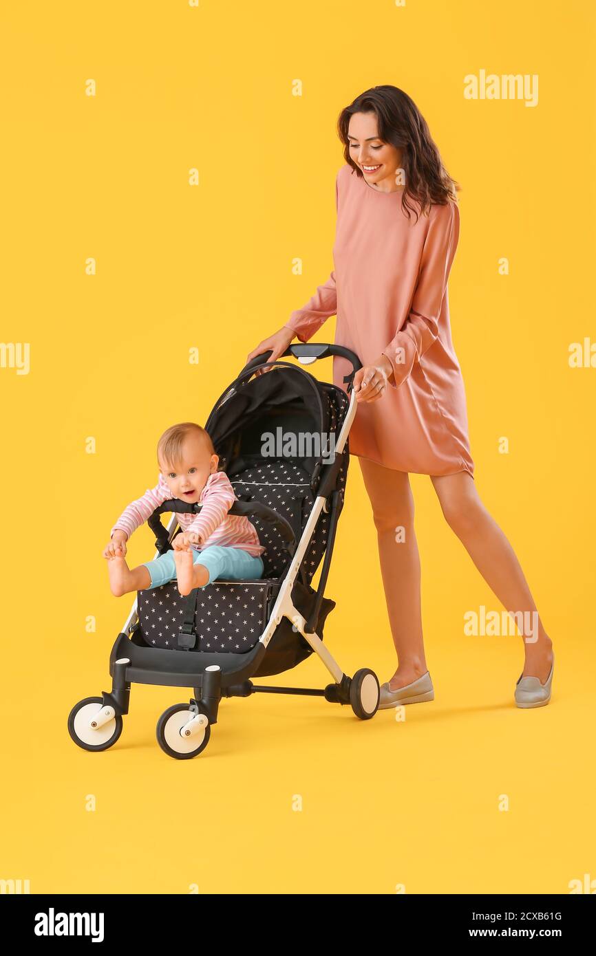 Woman and her cute baby in stroller on color background Stock Photo - Alamy