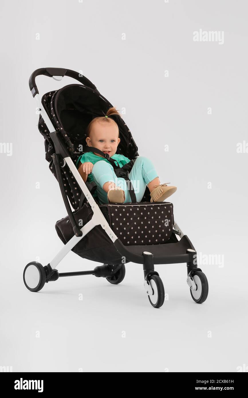 Cute little baby in stroller on light background Stock Photo - Alamy