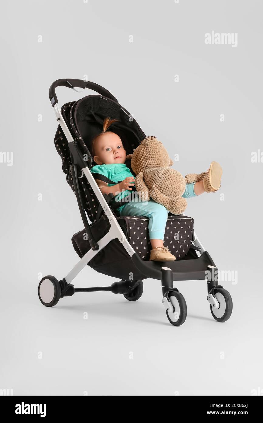 Cute little baby in stroller on light background Stock Photo - Alamy