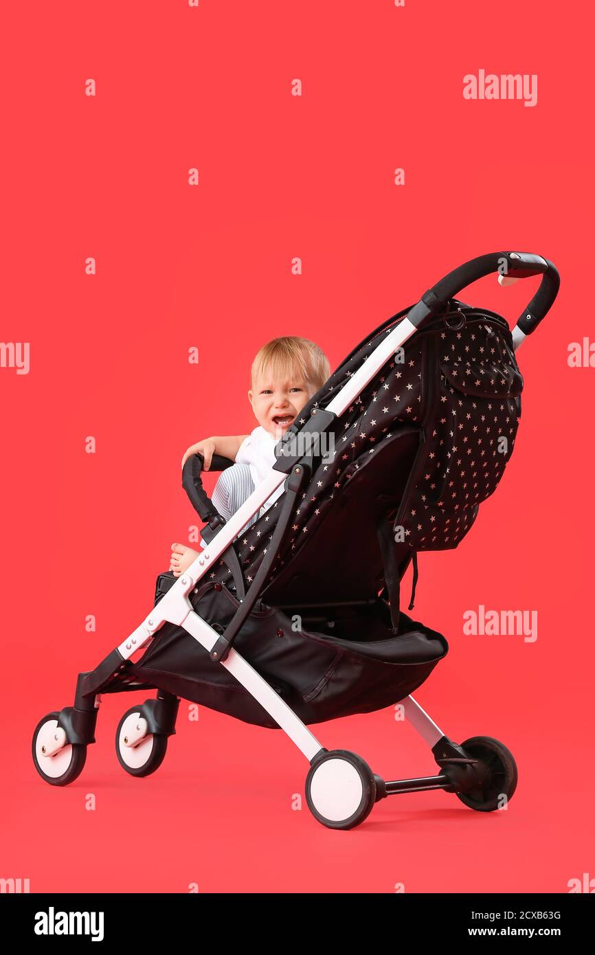 Cute little baby in stroller on color background Stock Photo - Alamy