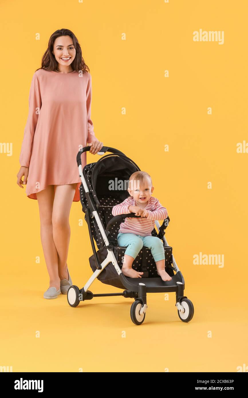 Woman and her cute baby in stroller on color background Stock Photo - Alamy