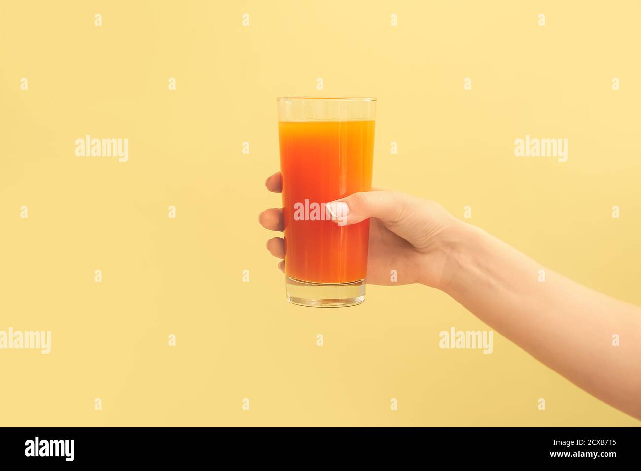 Hand with glass of fresh juice on color background Stock Photo - Alamy