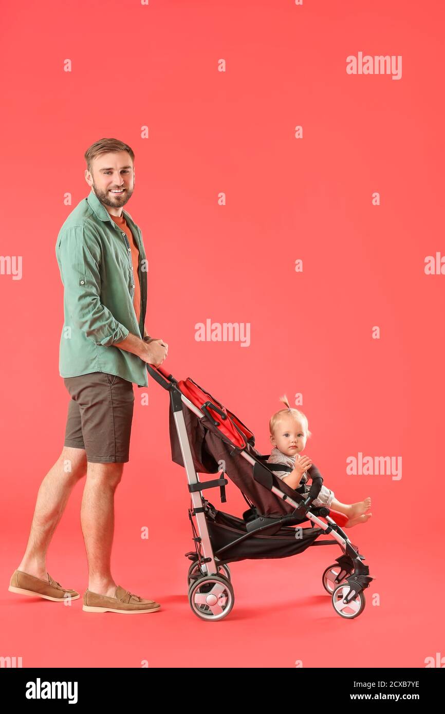 Father and his cute baby in stroller on color background Stock Photo ...